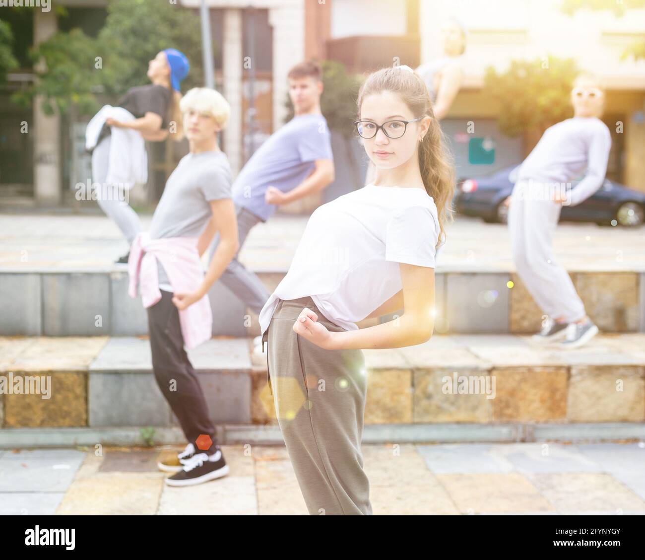 Positive girl dancing modern choreography with group of teenagers on ...