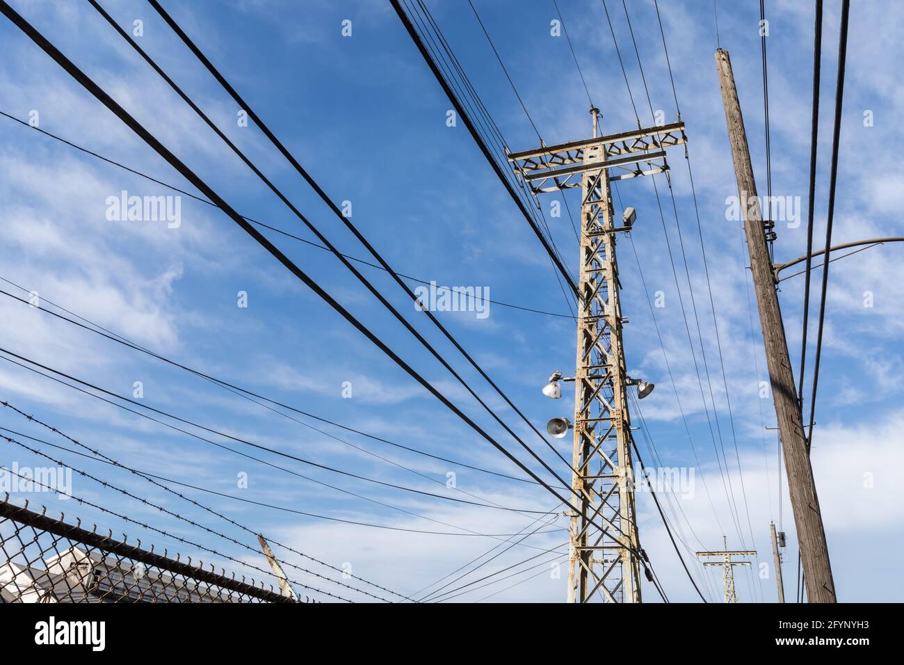 Multiple metal and wood power poles with lights and cables by a chain ...