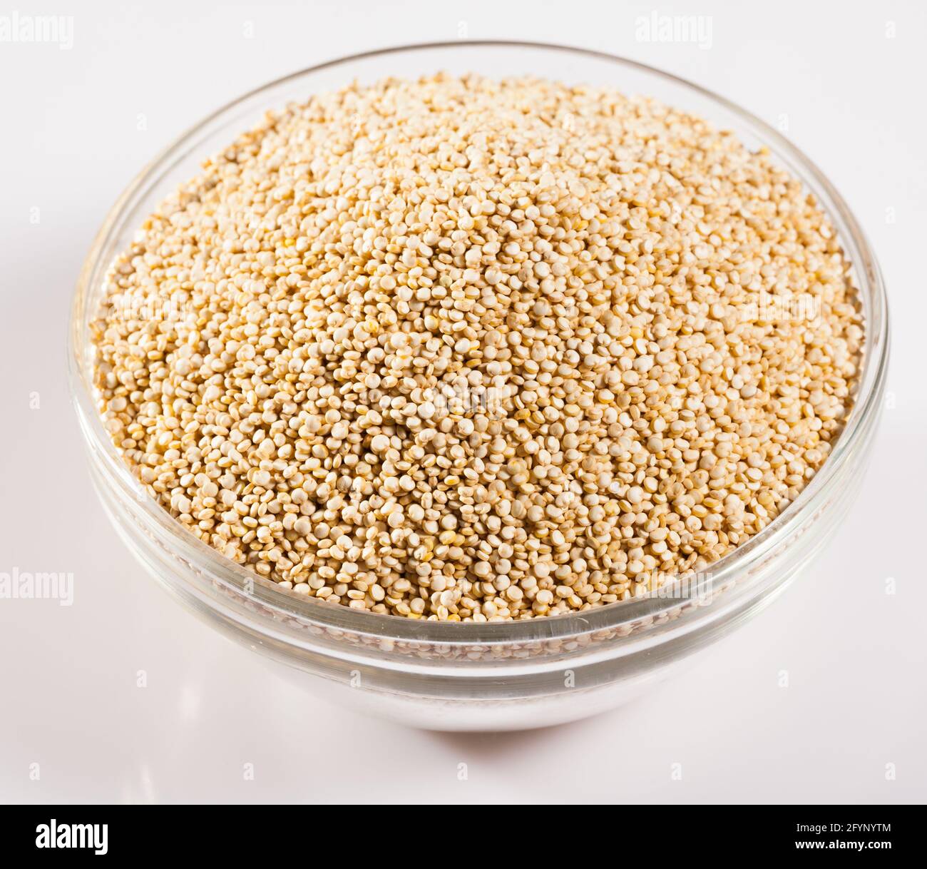 Glass bowl with raw quinoa seeds on white surface. Healthy and ...