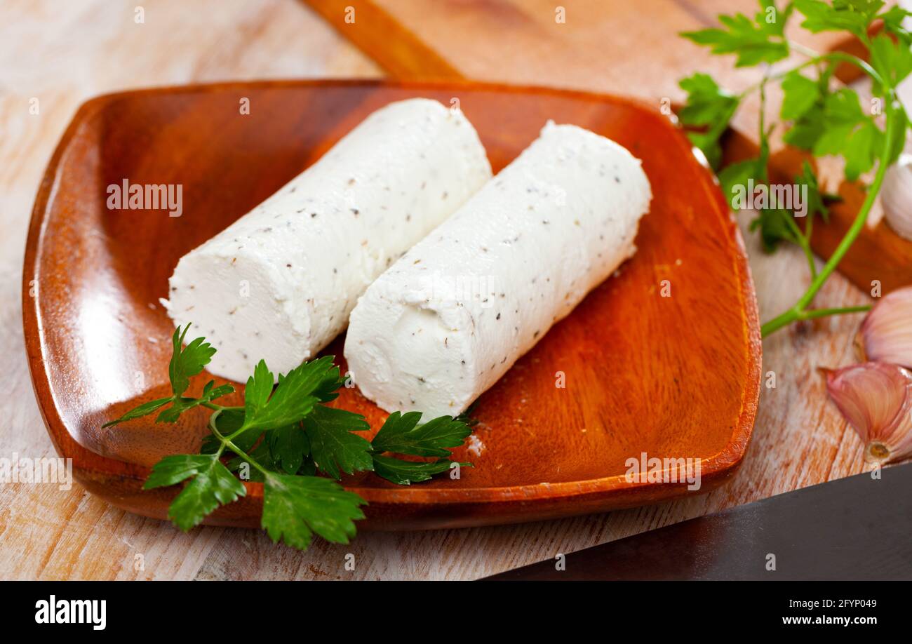 Fresh log shaped goat cheese with garlic and herbs served on plate on ...