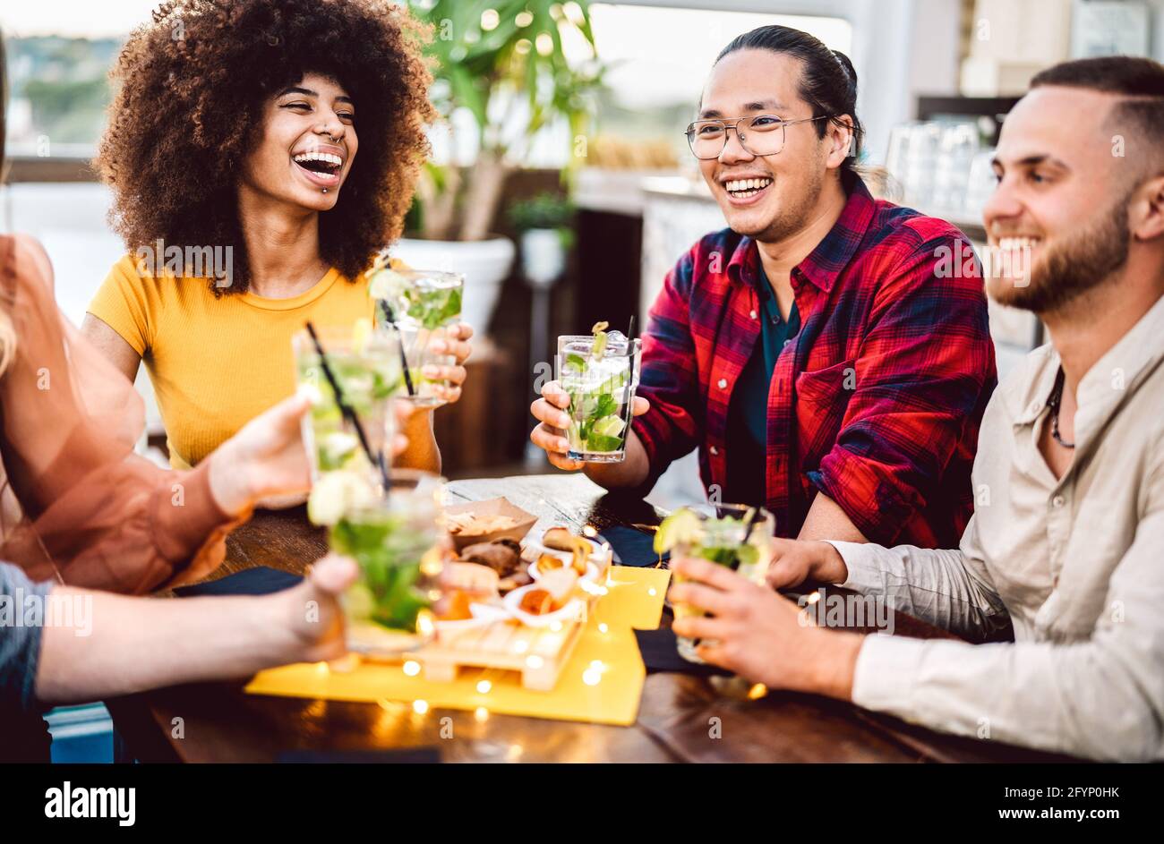 Young friends toasting mojito drinks at fashion cocktail pub restaurant ...