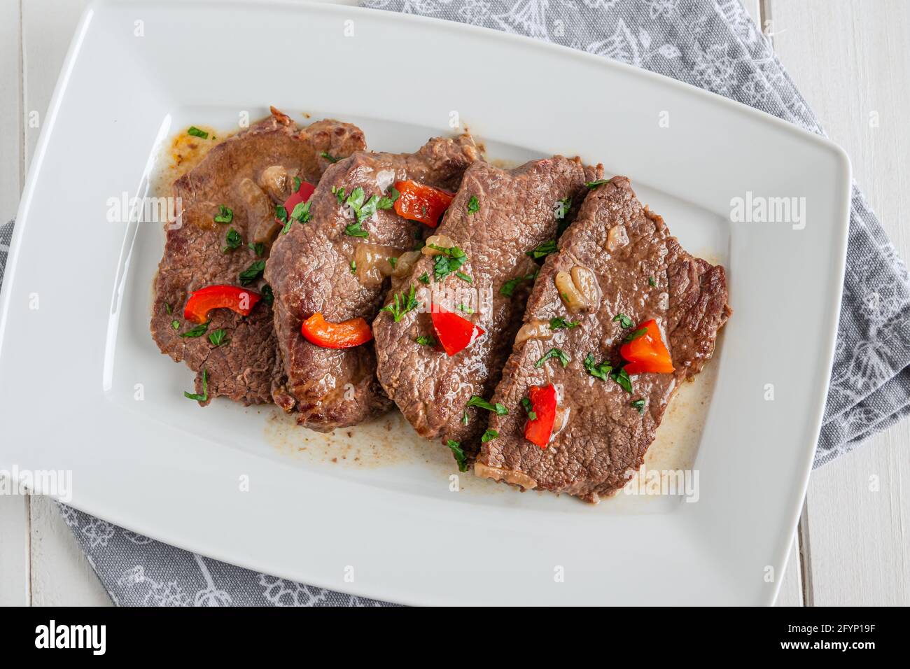 Braised beef cooked with red pepper, served on a plate Stock Photo - Alamy