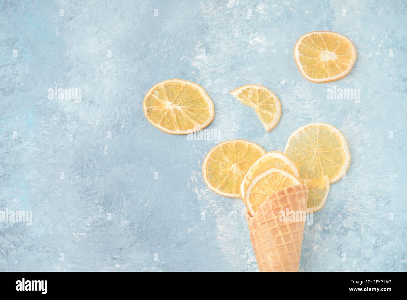 dried lemon slices in a ice cream cone on blue background with copy ...