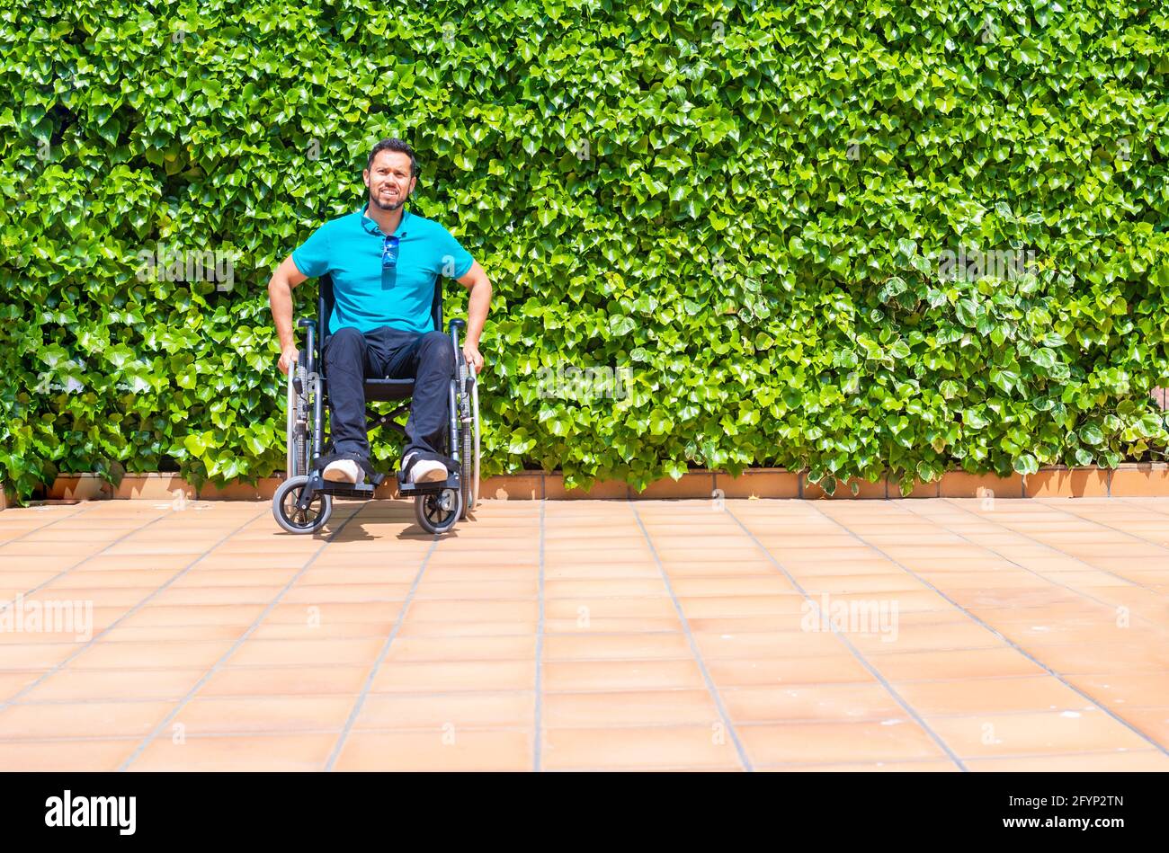Hispanic man in a wheelchair rolling forward on the tiled ground ...
