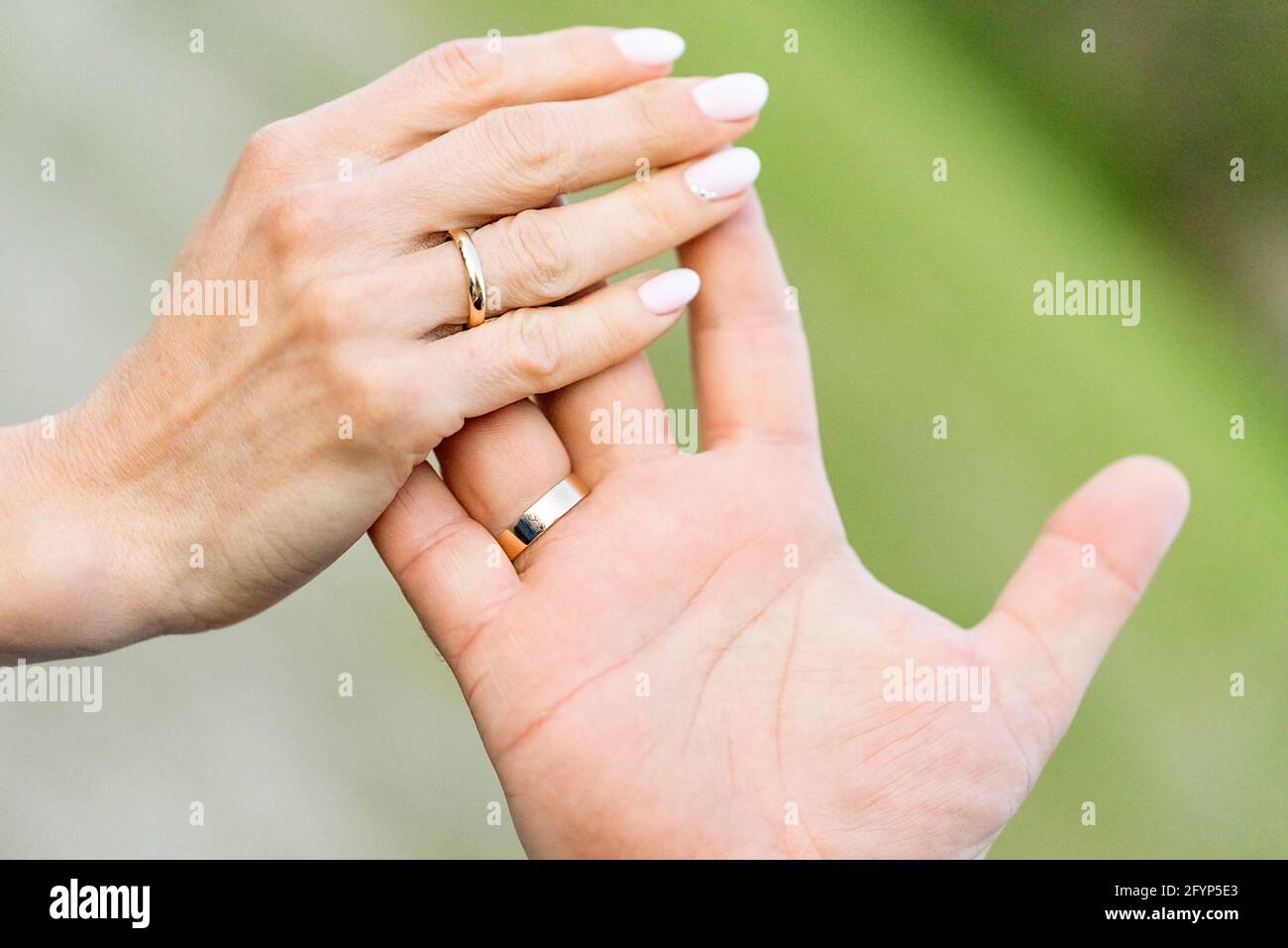 Close up of clasped hands with wedding rings. Marriage symbol. Gold ...