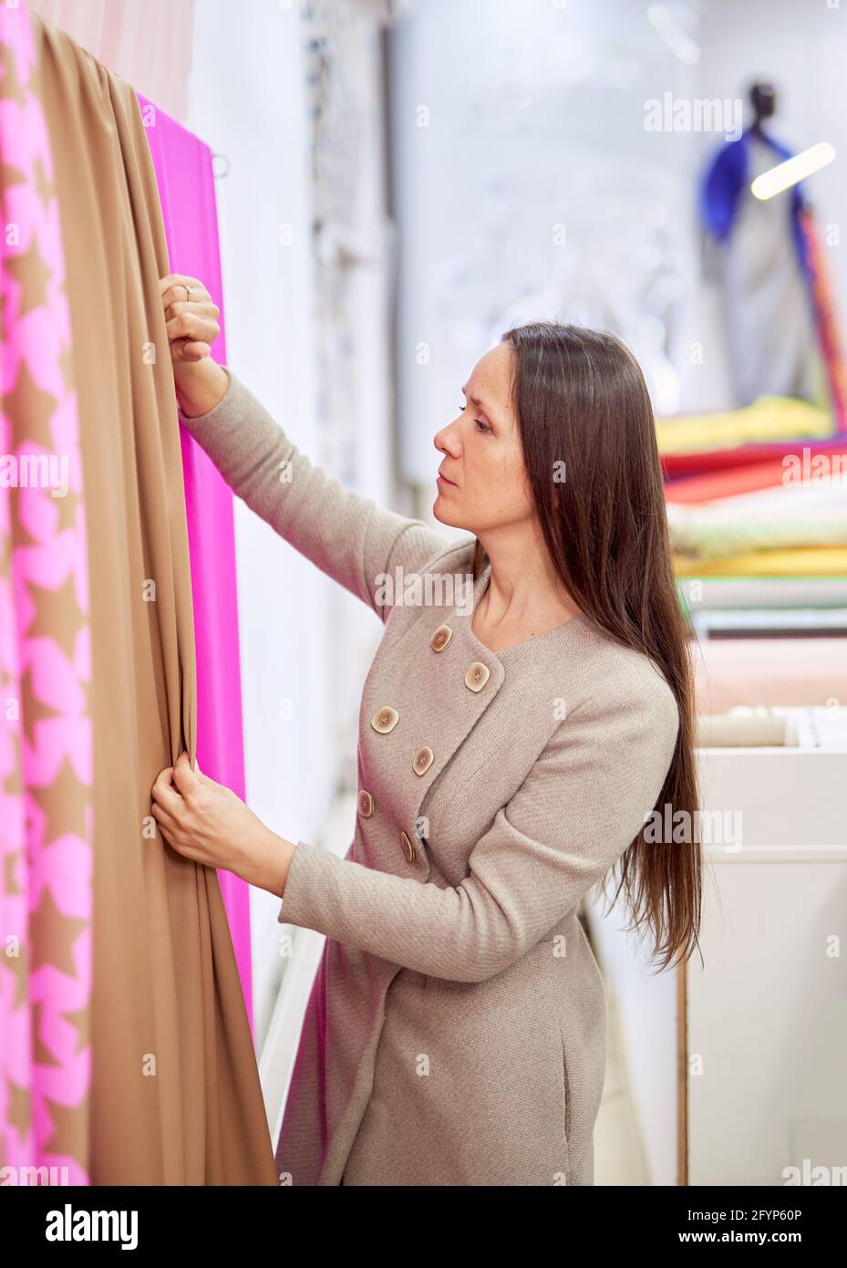 Caucasian brunette girl seamstress or tailor works in atelier boutique ...