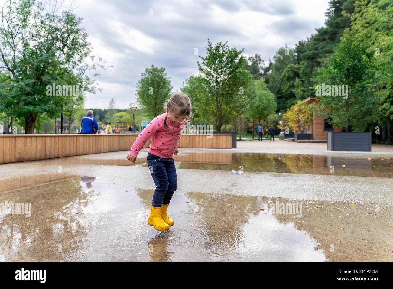 happy child girl running and jumping in puddles after rain in summer ...
