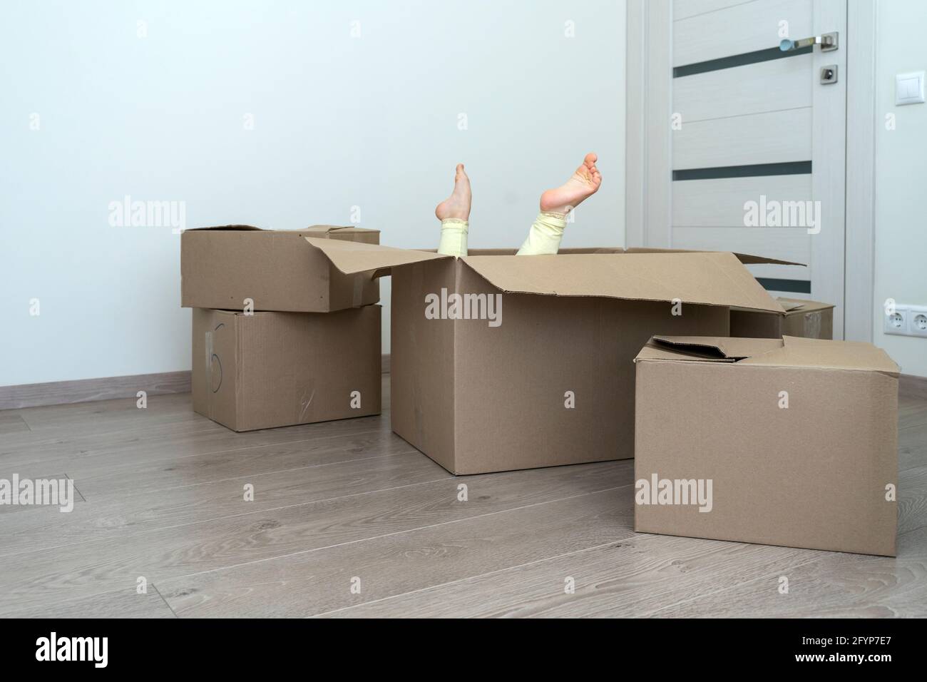 cardboard boxes in the room. the baby's legs are sticking out of the ...