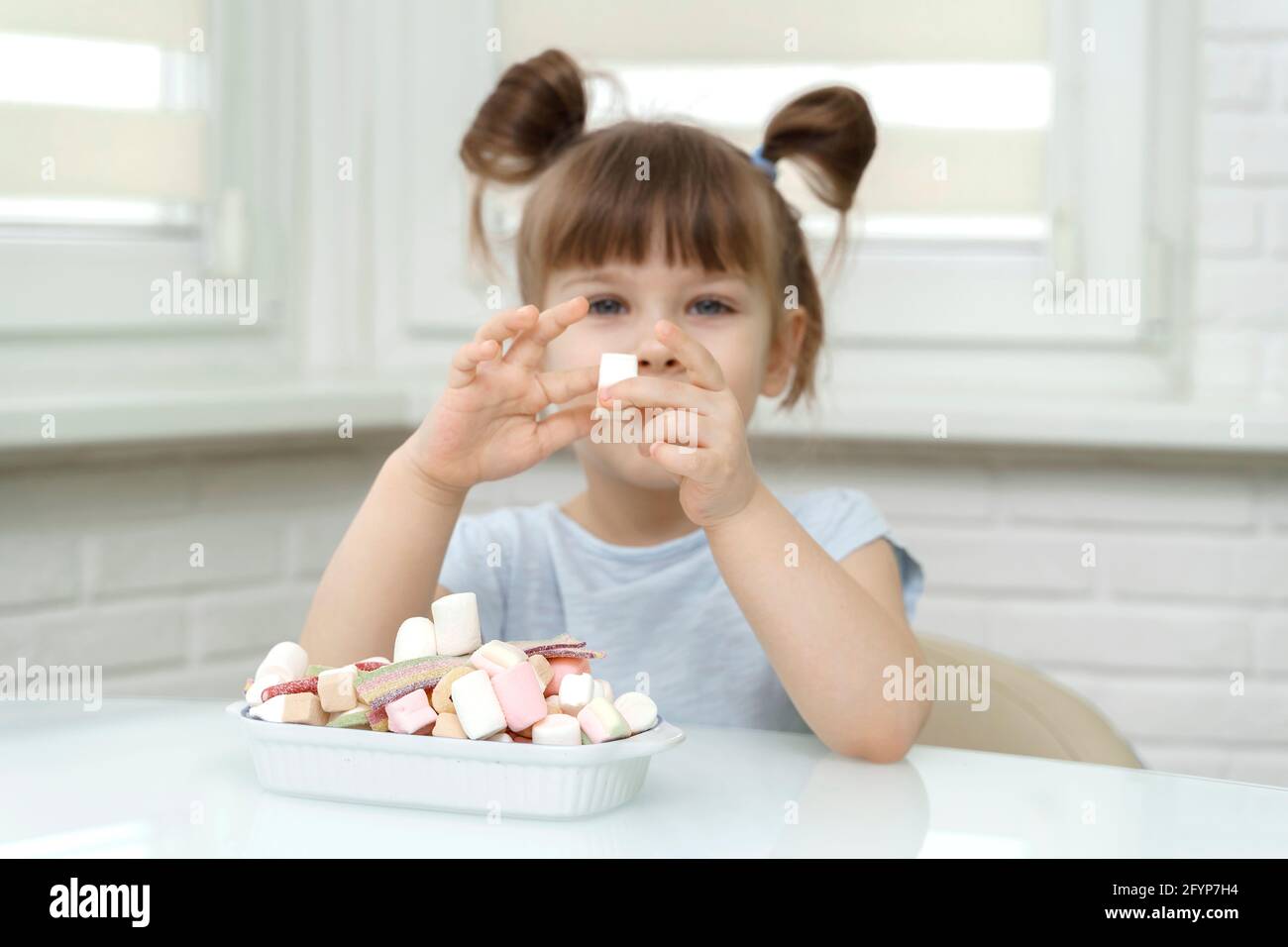 happy contented little girl eating marshmallows from a plate full of ...