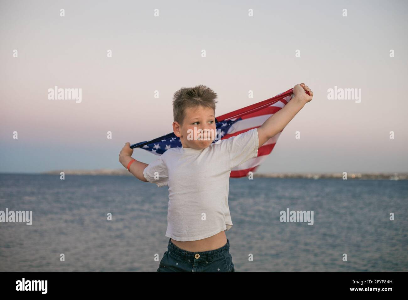 Little boy lets the american flag fly in his hands on the wind at the ...