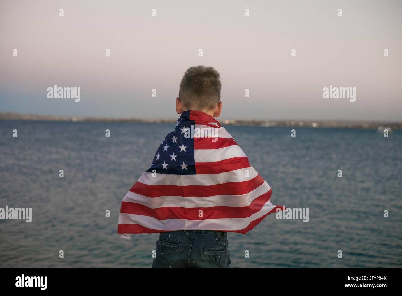 Little boy lets the american flag fly in his hands on the wind at the ...