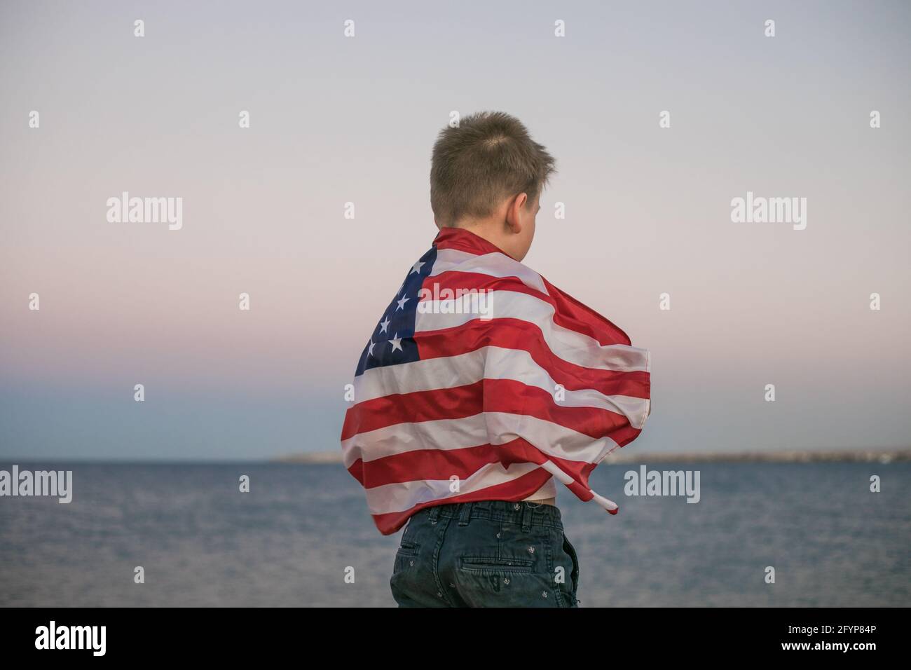Little boy lets the american flag fly in his hands on the wind at the ...