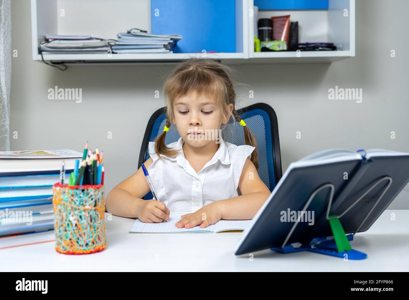 Cute little girl writing her homework Stock Photo - Alamy