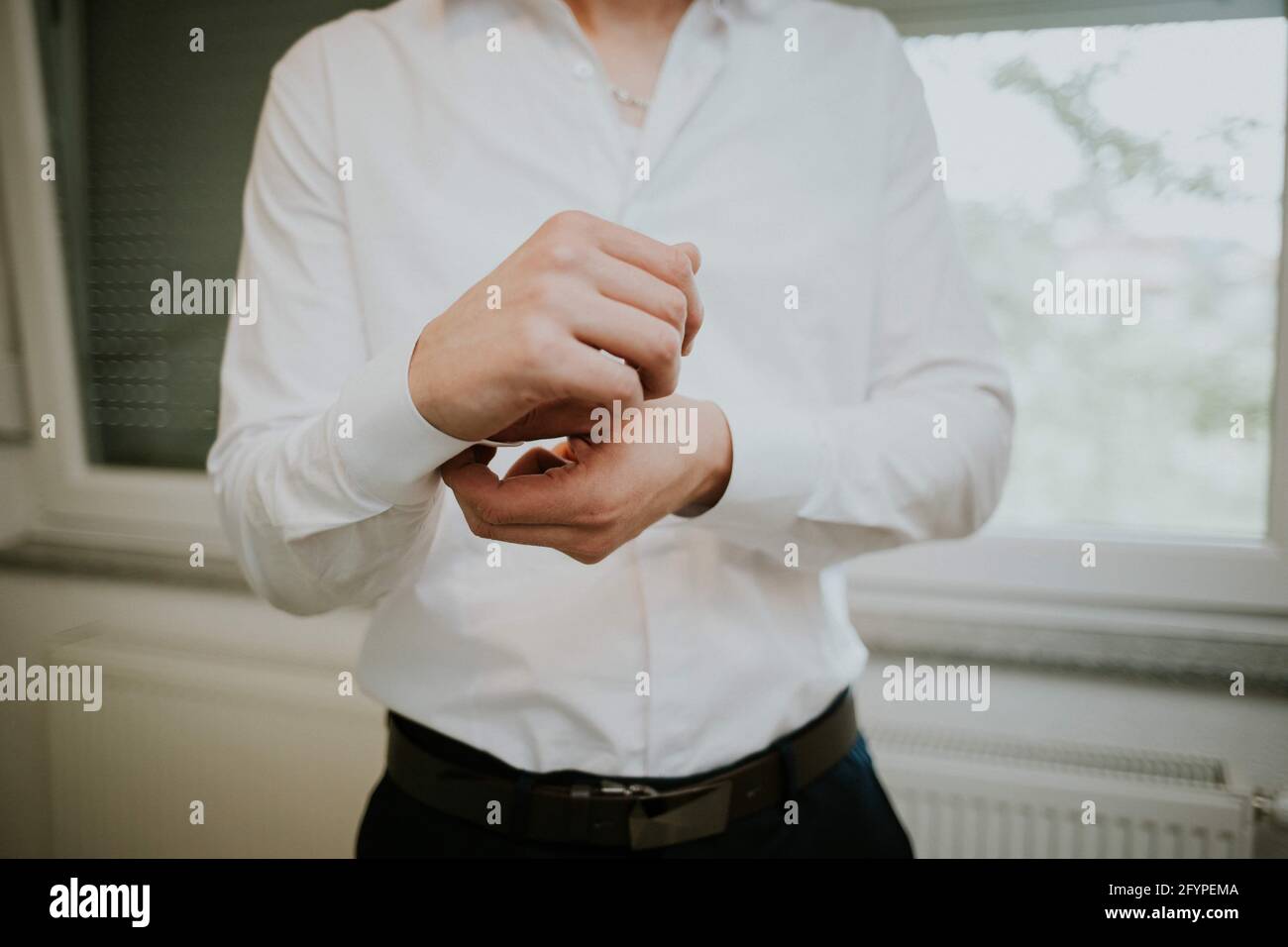 Man buttoning his white shirt Stock Photo - Alamy
