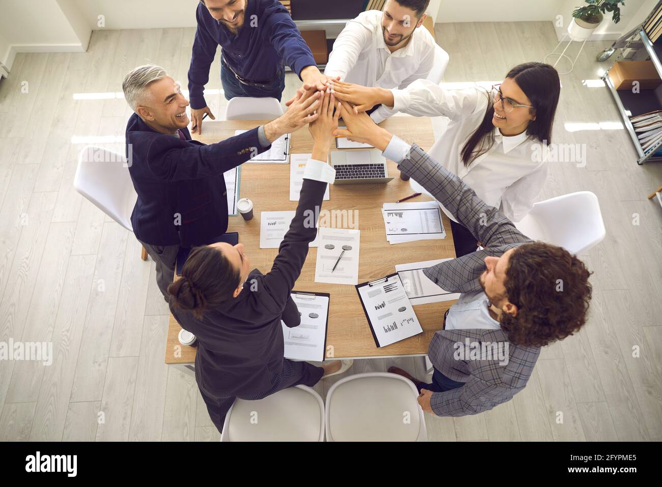 Happy sales team standing around an office table and giving each other ...