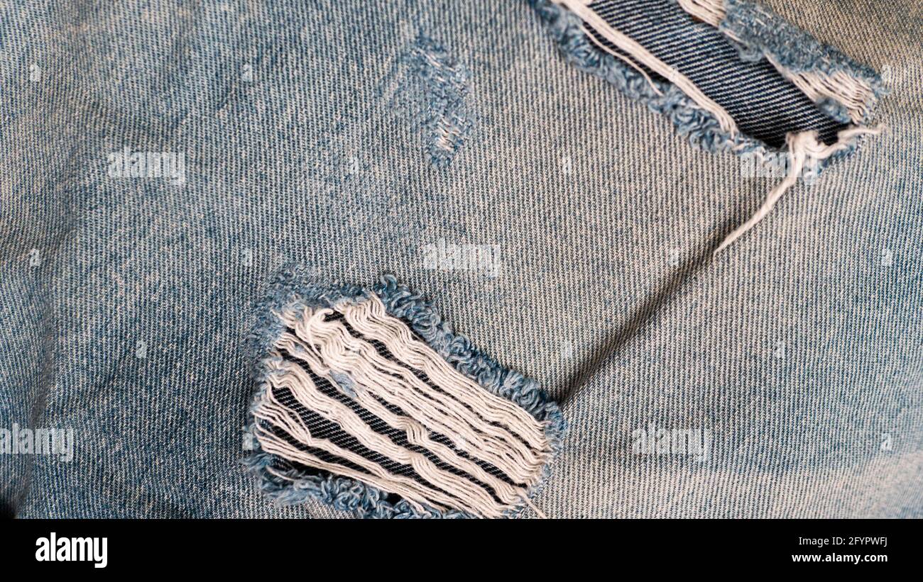 Denim background. Blue ripped jeans close-up. Denim Stock Photo - Alamy
