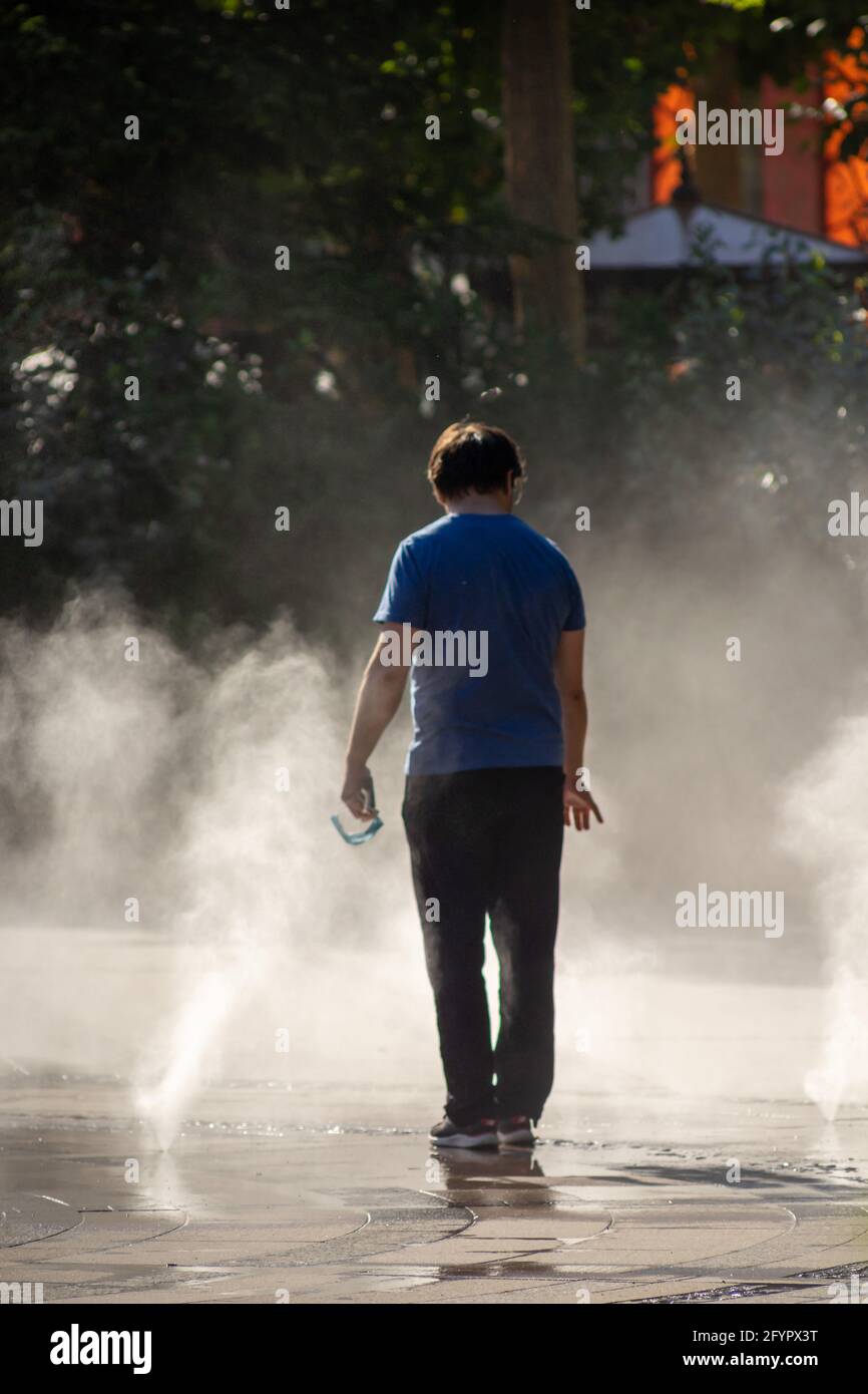 Man sitting in water vapor in a park Stock Photo - Alamy
