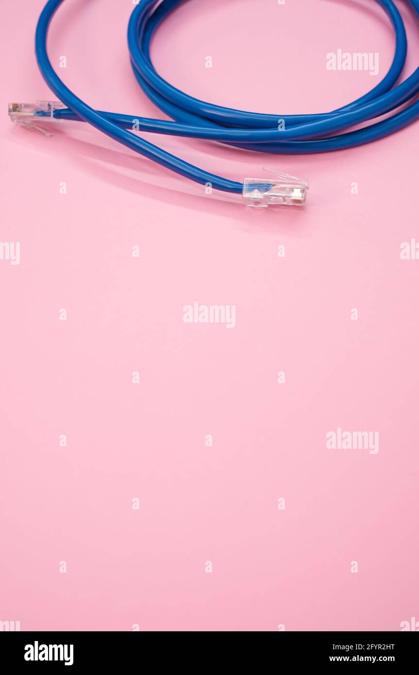 A vertical shot of a blue LAN cable isolated on a pink background Stock ...