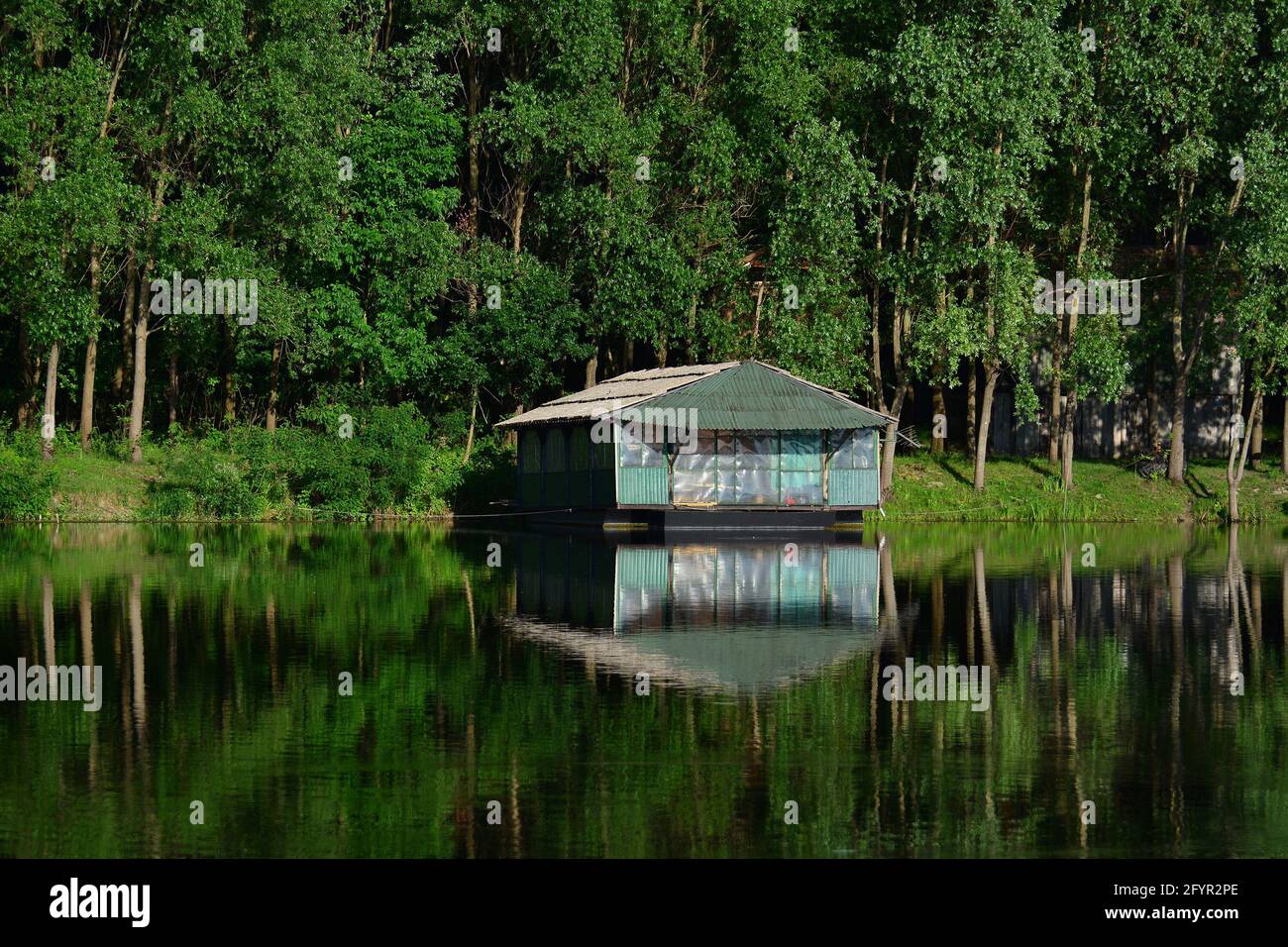 Wooden house on a river with its reflection surrounding by trees Stock ...