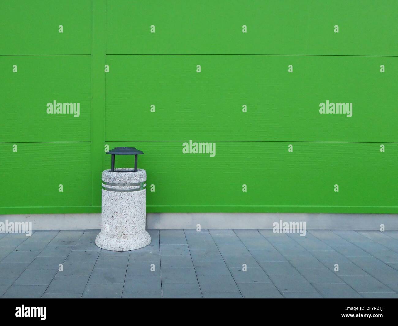 Stone litter rubish bin in front of a green wall Stock Photo - Alamy