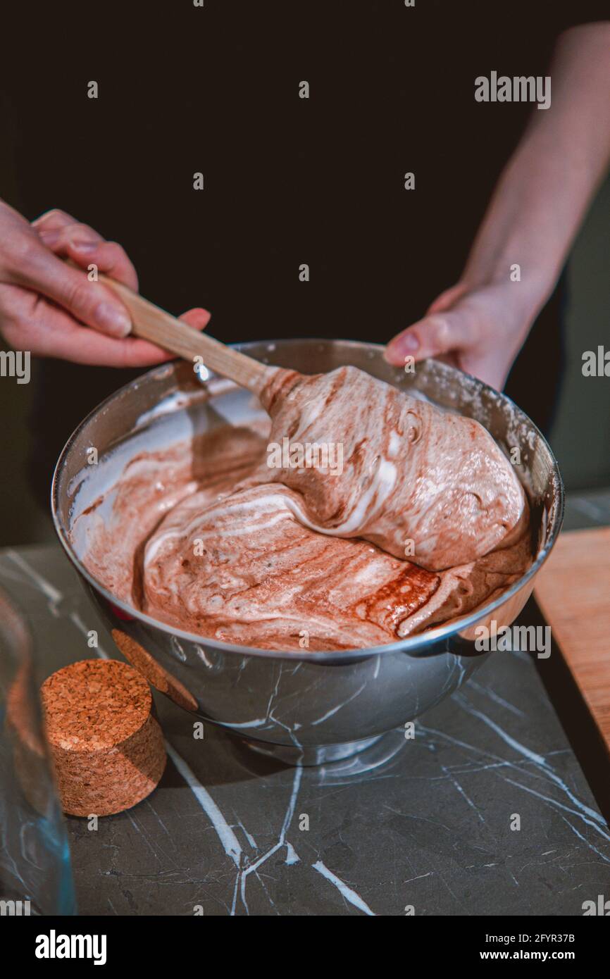 Selective focus shot of a person mixing chocolate with the dough in a ...
