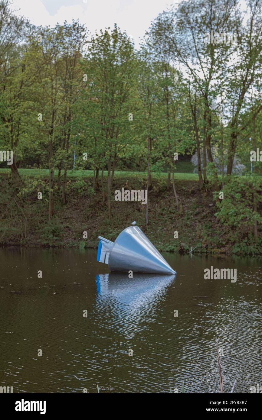 Metallic cone on the river in front of a forest with thin trees Stock ...