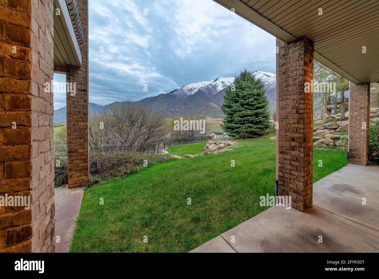 Beautiful wide garden with fresh green grass seen through brick columns ...