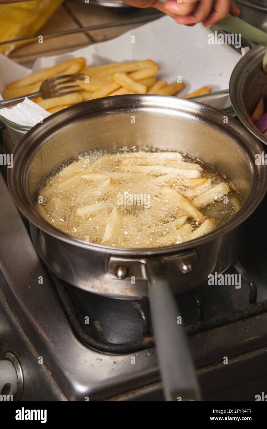Vertical shot of a pot full of french fries frying in the oil Stock ...