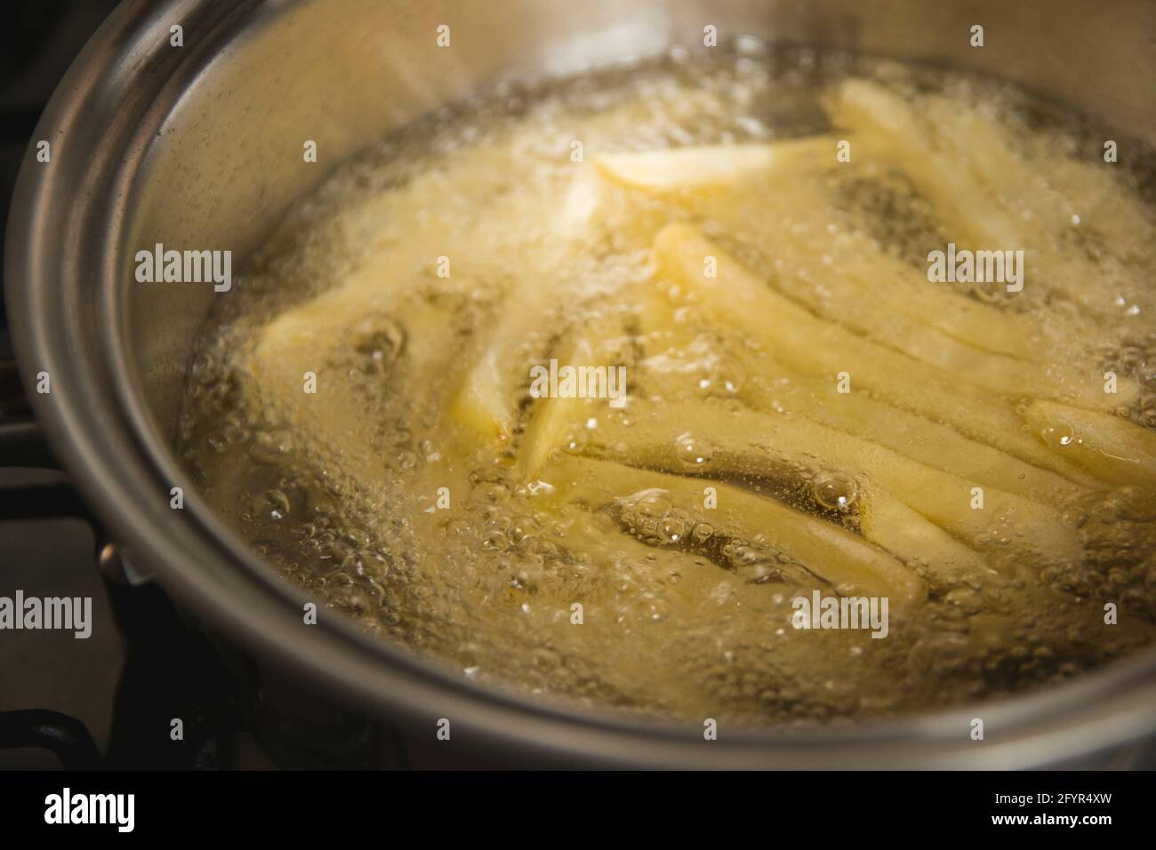 Closeup of a pot full of french fries frying in the oil Stock Photo - Alamy