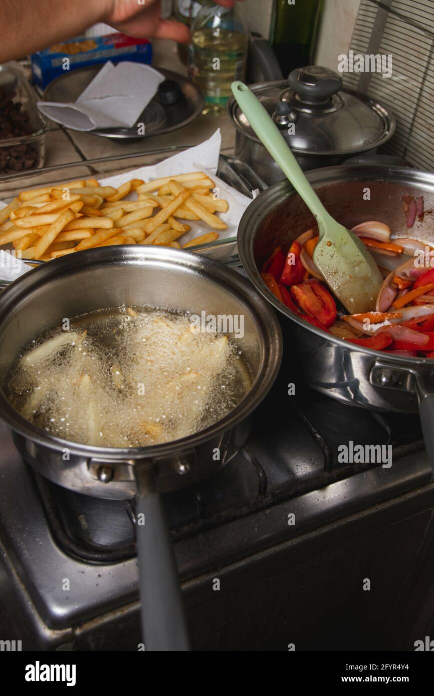 Vertical shot of a pot full of french fries frying in the oil next to ...