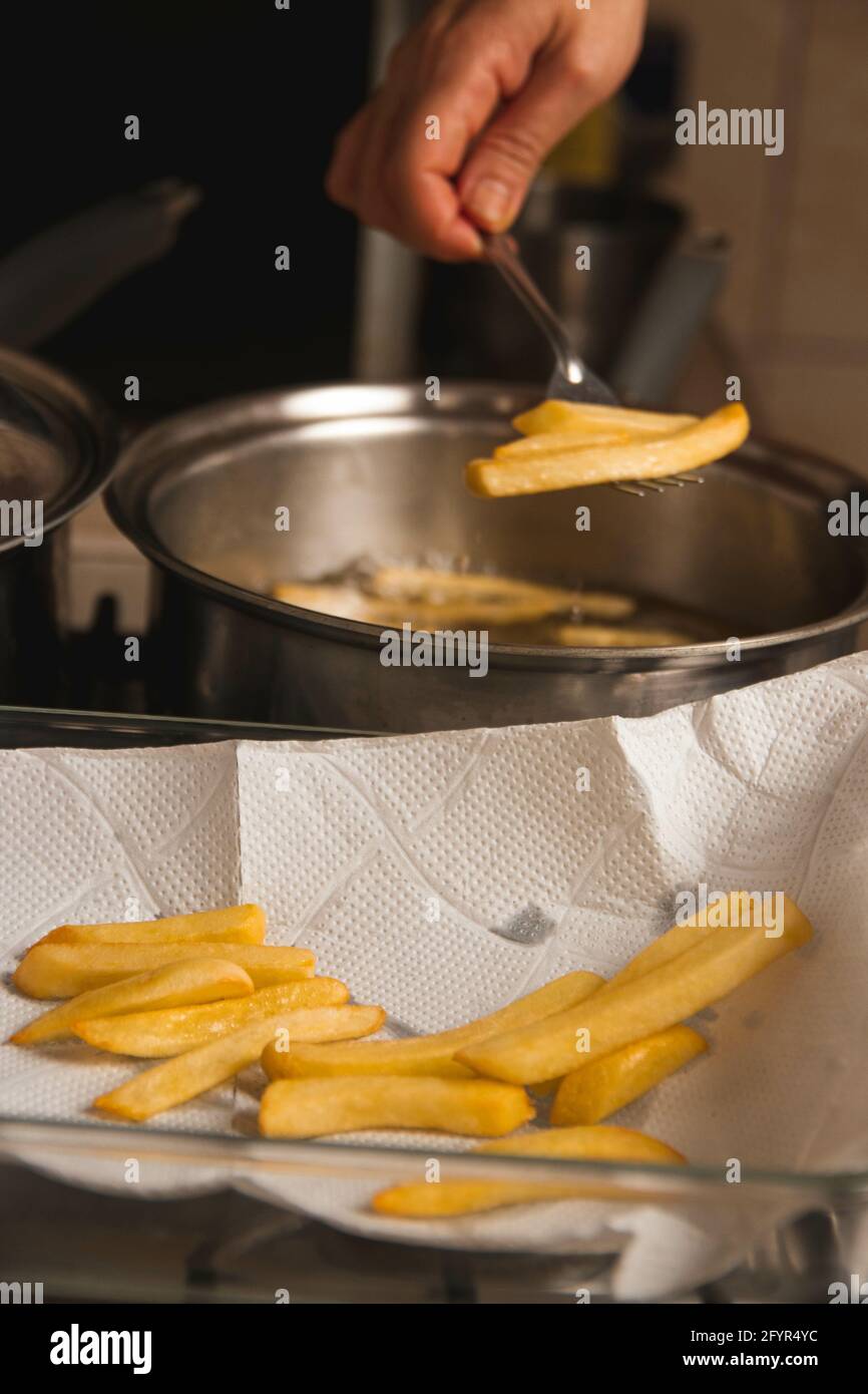 Vertical shot of a hand putting golden crispy french fries on the ...