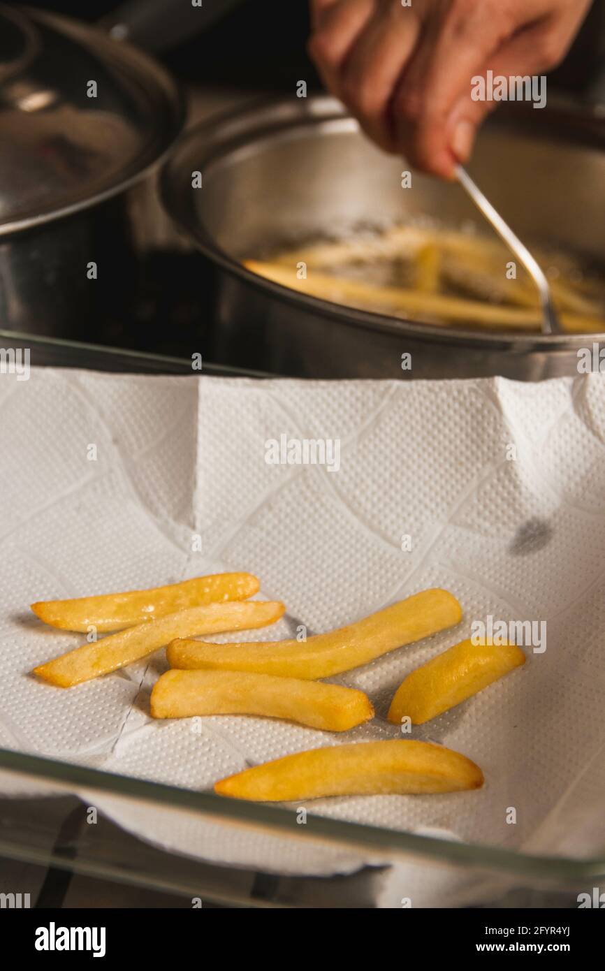 Vertical shot of a hand putting golden crispy french fries on the ...