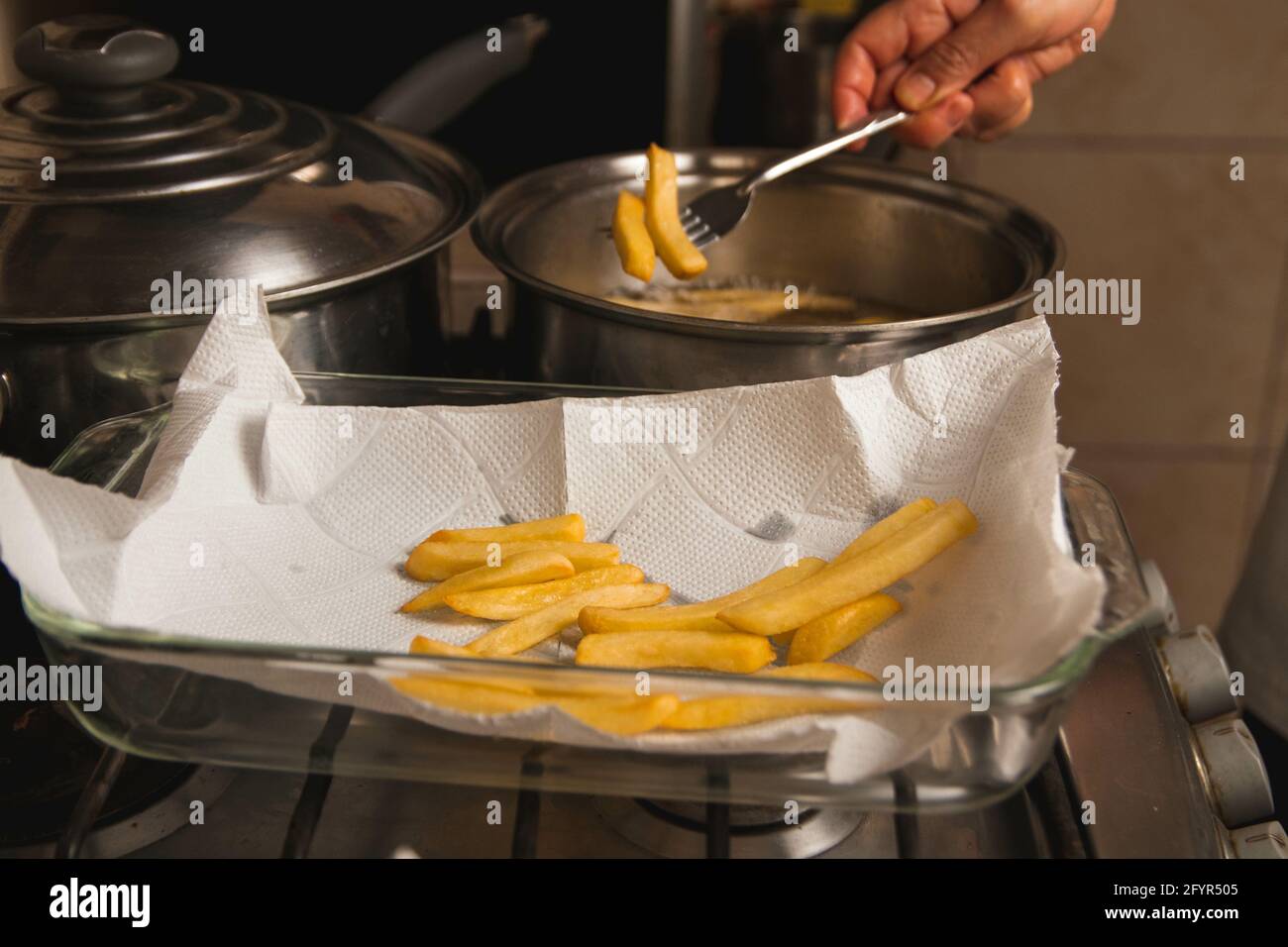 Closeup of a hand putting golden crispy french fries on the napkin ...