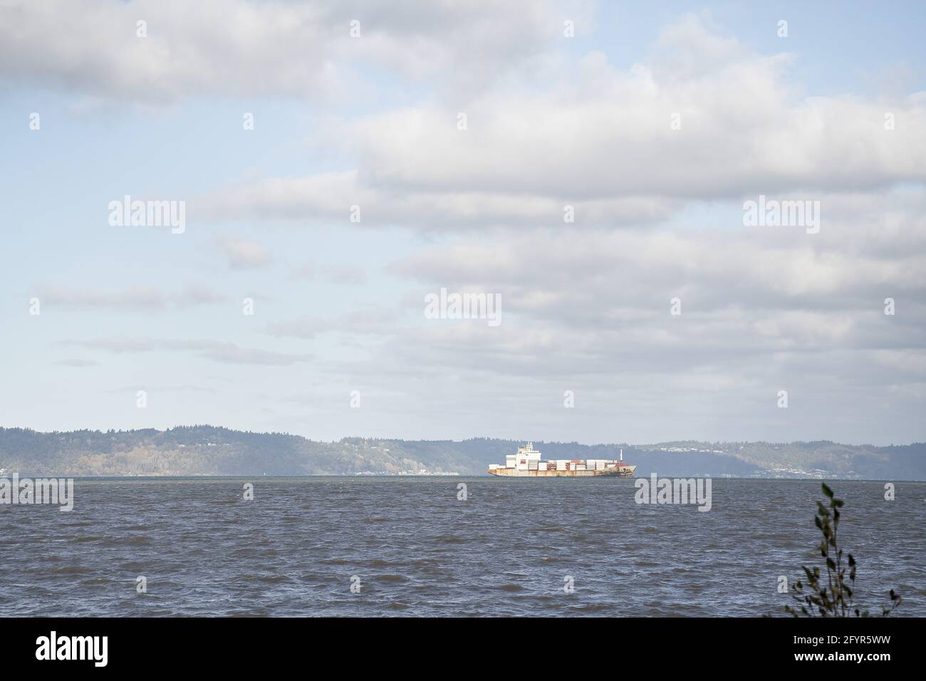 Container ship floating on the sea waters under the cloudy blue sky ...