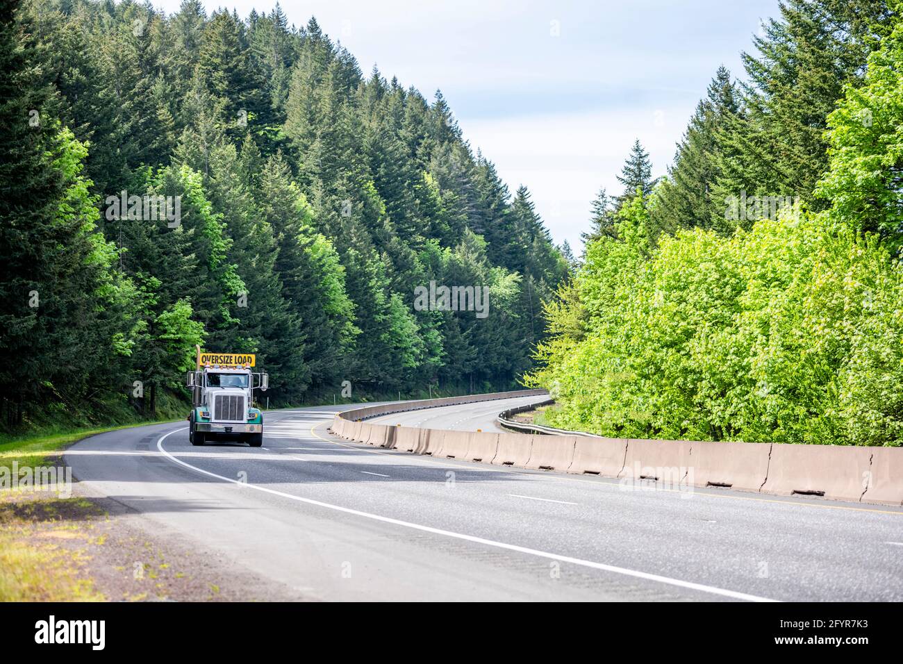 Green classic big rig industrial semi truck with oversize load sign on ...