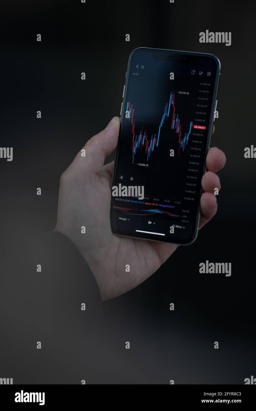 Male hand holding smartphone with financial forex graph chart on screen ...