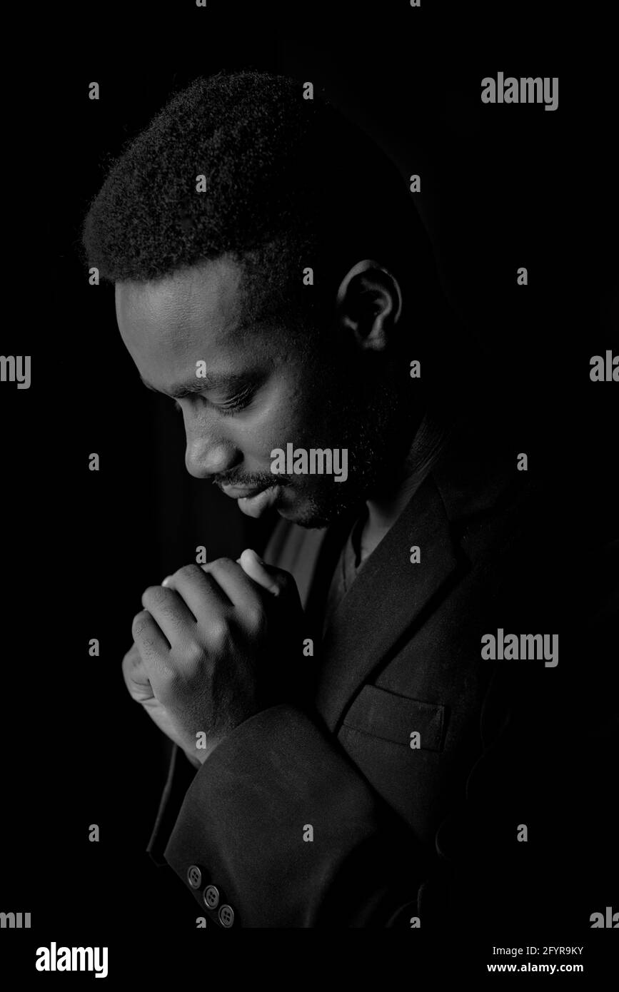 African man praying for god in the dark room.Low key lighting style ...