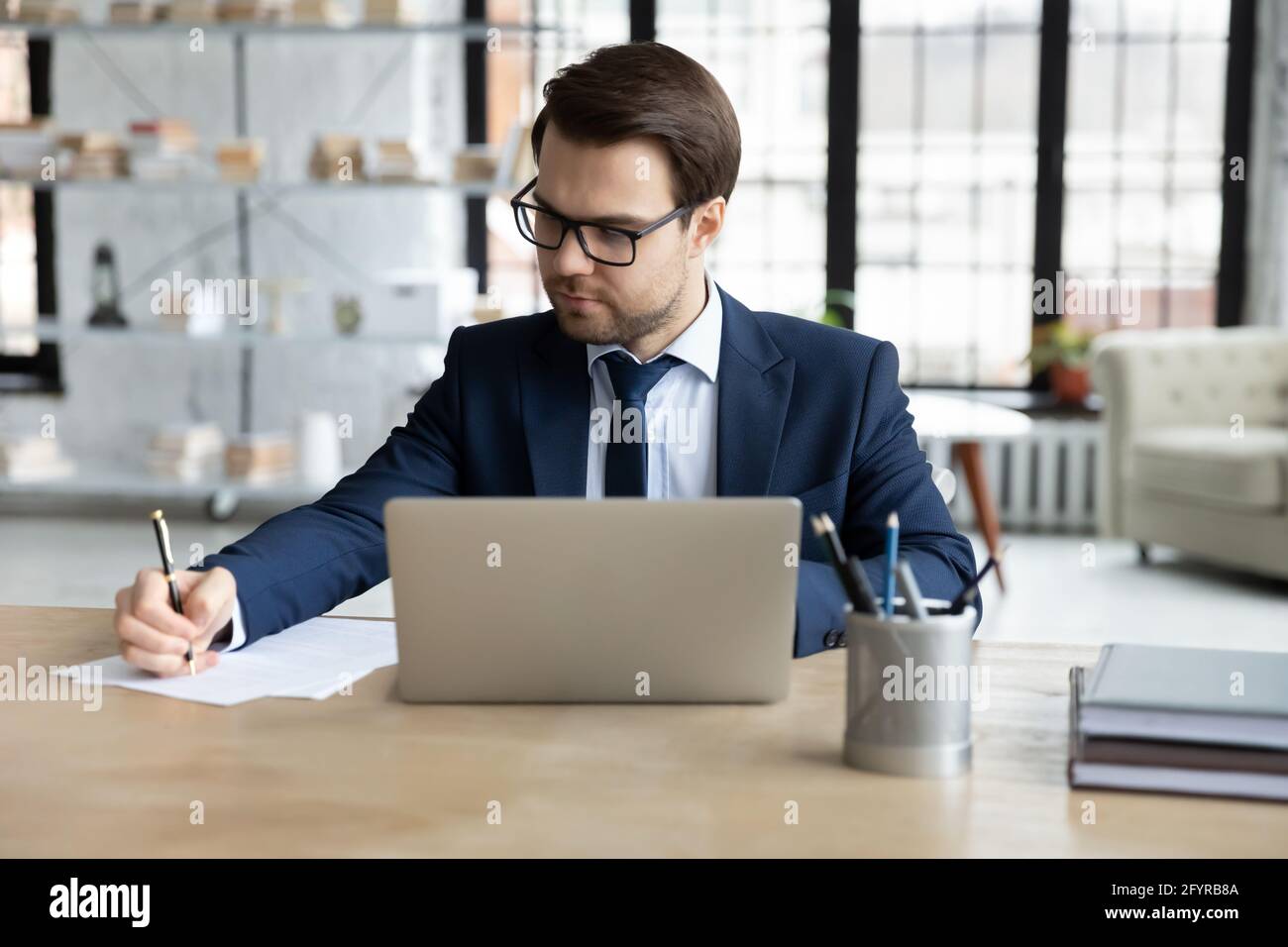 Serious male legal expert checking document at workplace Stock Photo ...