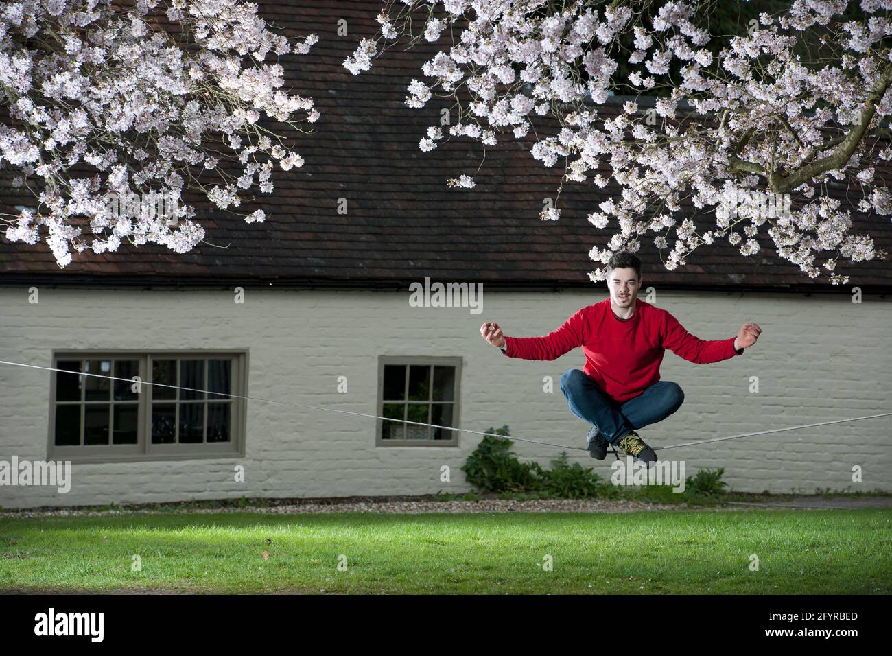 young man practising his balance on a slack line between two trees ...