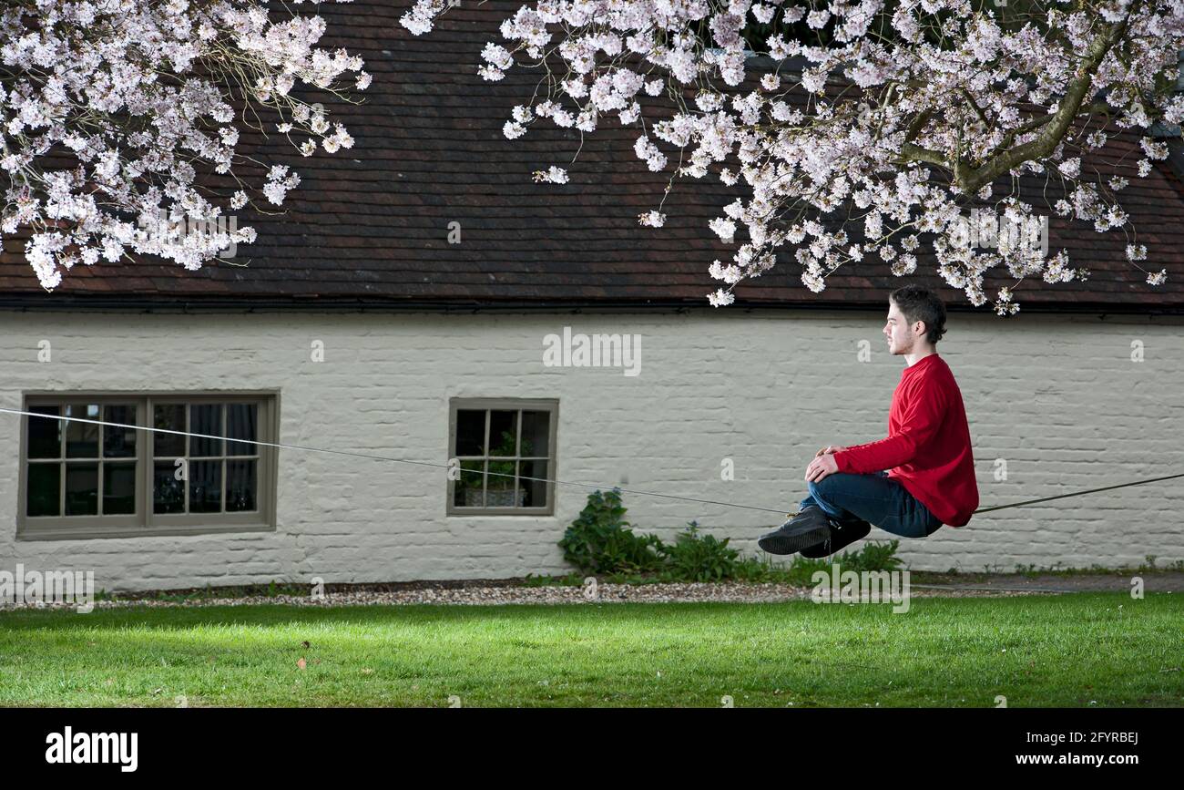young man practising his balance on a slack line between two trees ...