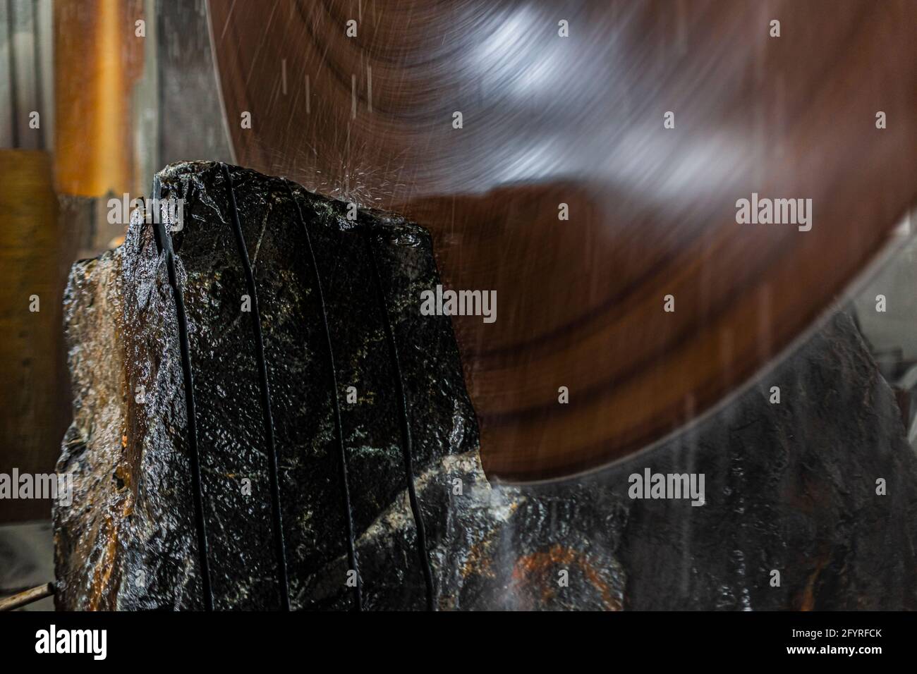 Large industrial cutting machine cuts gray granite stone into slabs ...