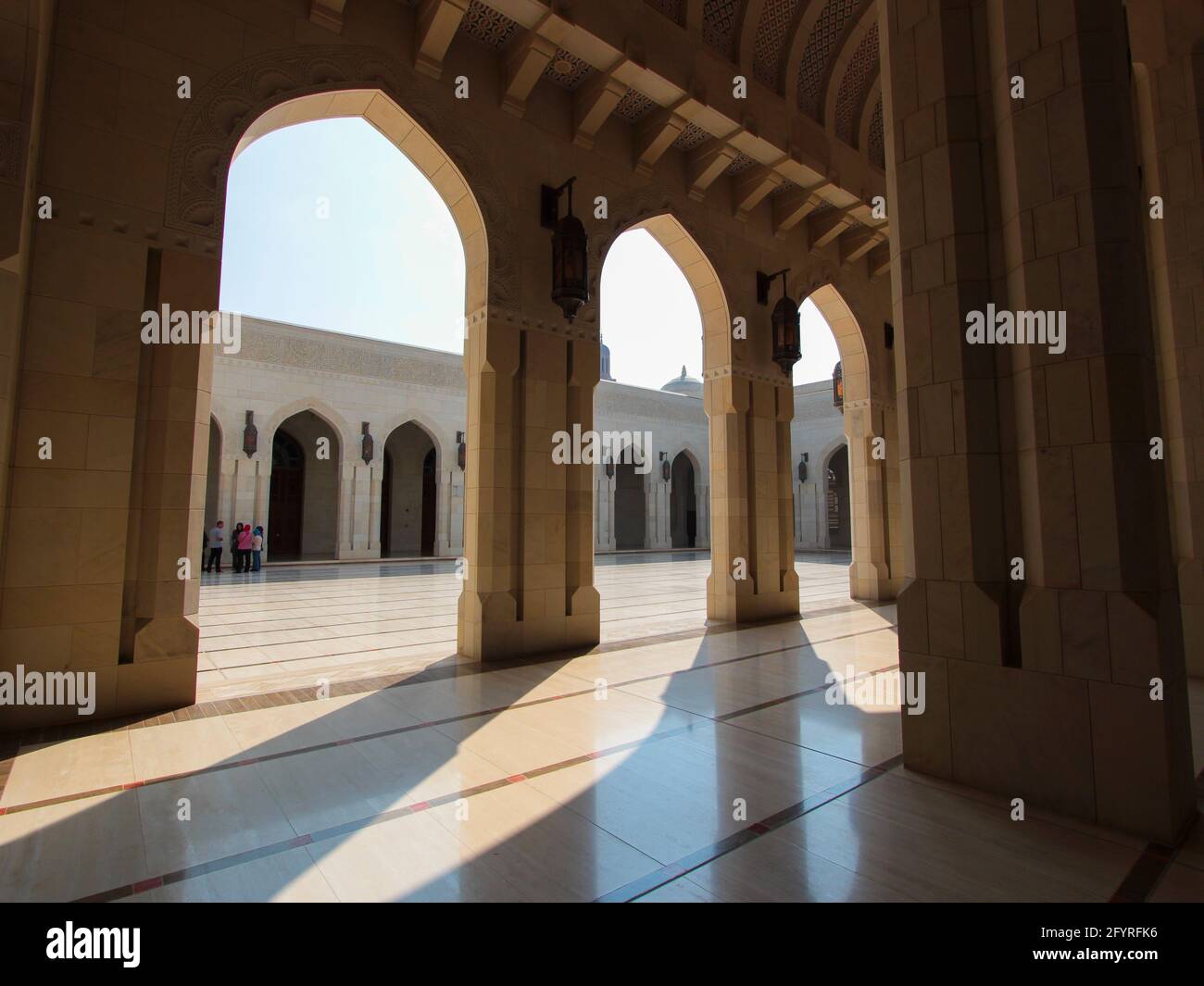Sunny courtyard and columned arcade in the shadows at the Sultan Qaboos ...