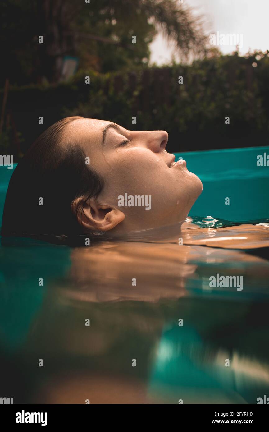 Vertical closeup shot of a relaxed female laying in a pool Stock Photo ...