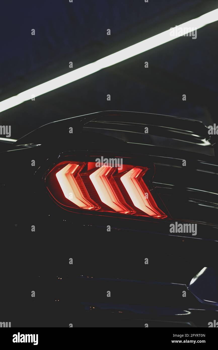 A vertical closeup shot of a black sports car red backlight at night ...