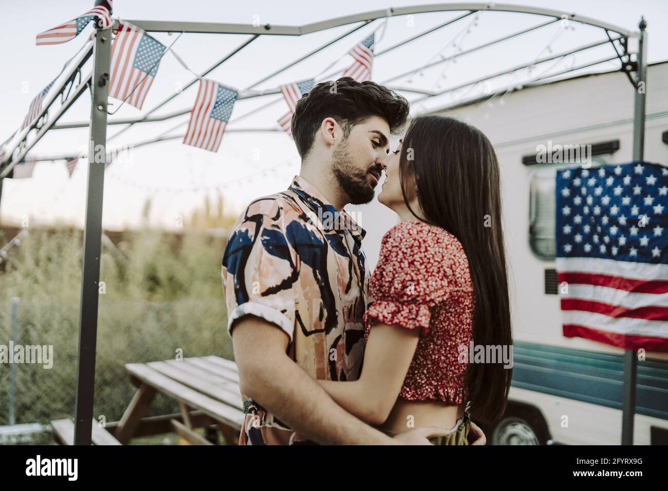 A beautiful Spanish couple kissing on background of the US flag - US ...