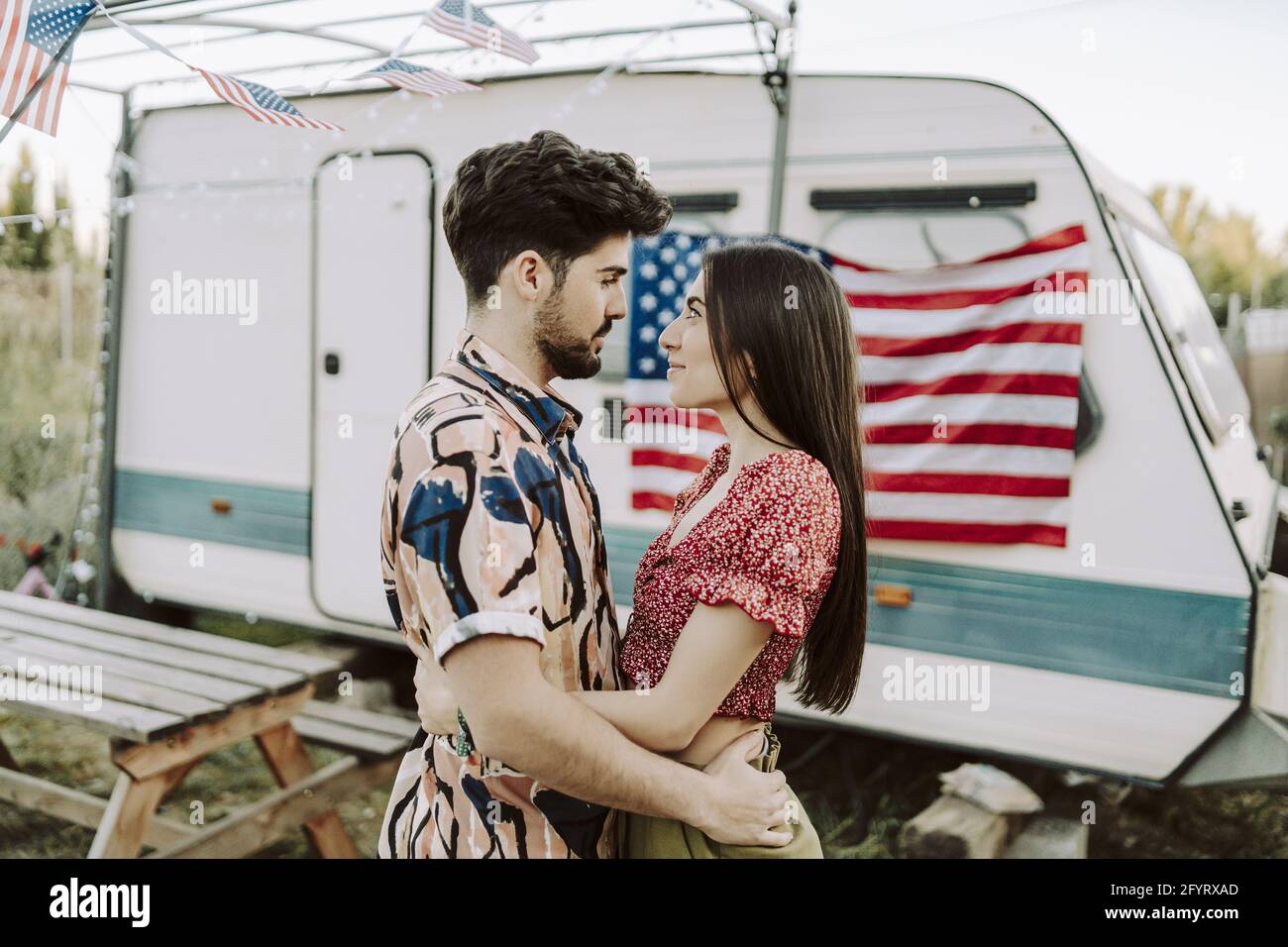 A beautiful Spanish couple hugging on background of the US flag - US ...