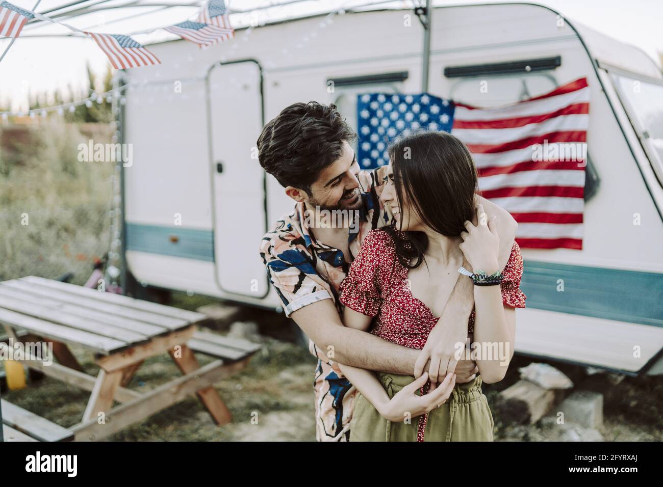 A beautiful Spanish couple hugging on background of the US flag - US ...