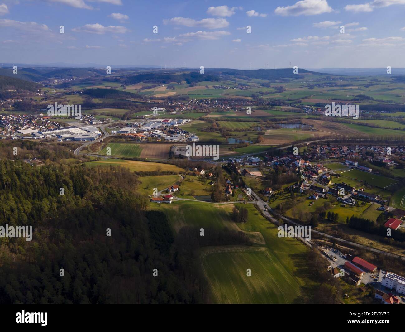 A bird's-eye view of a rural town in the green fields with ponds ...