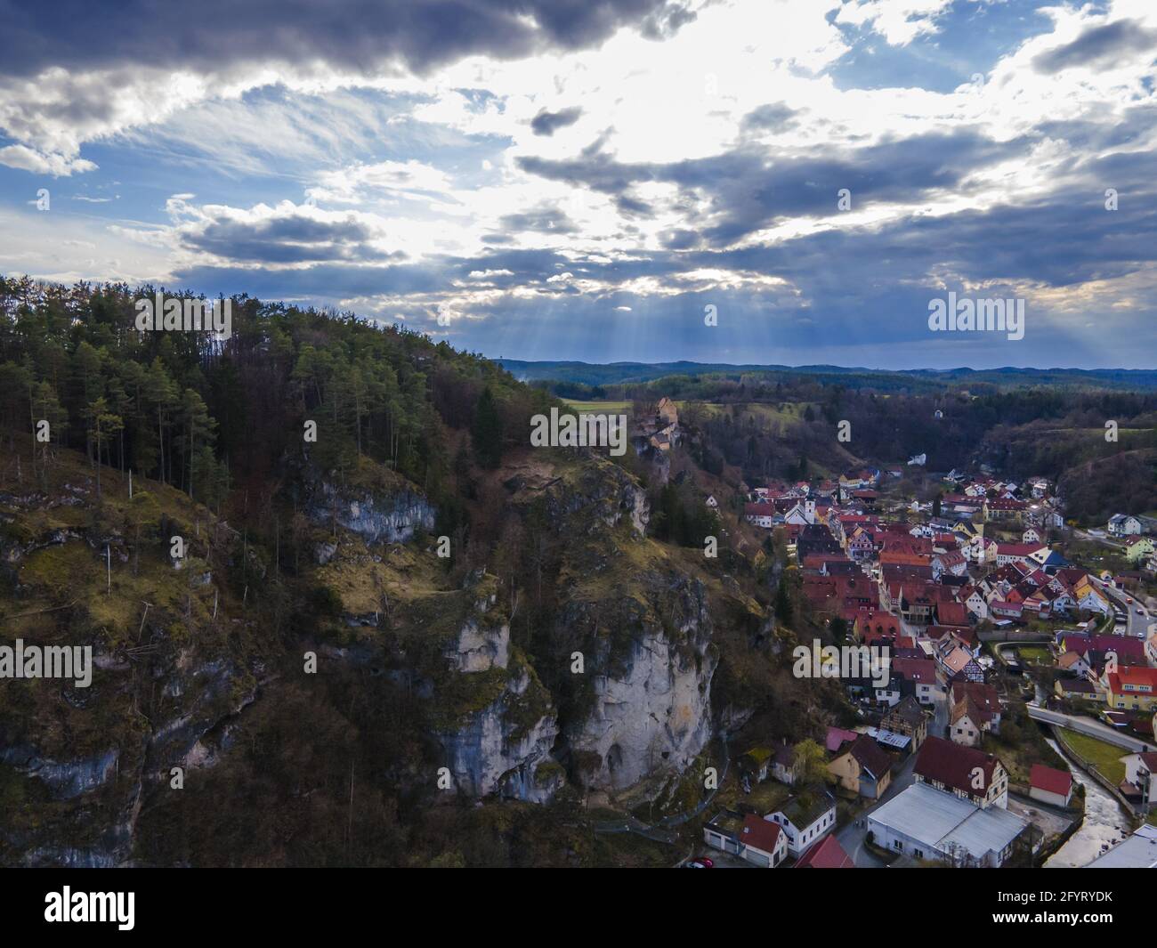 An eerie scenery of a small town in the valley in sunbeams at dawn ...