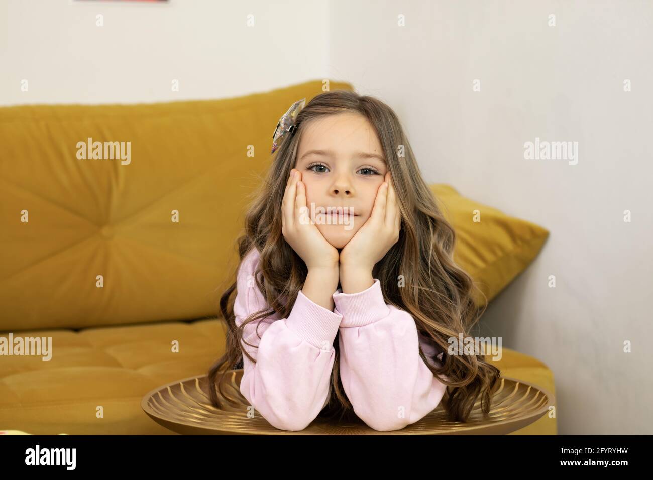 A cute little girl sitting on a sofa with hands under her head Stock ...